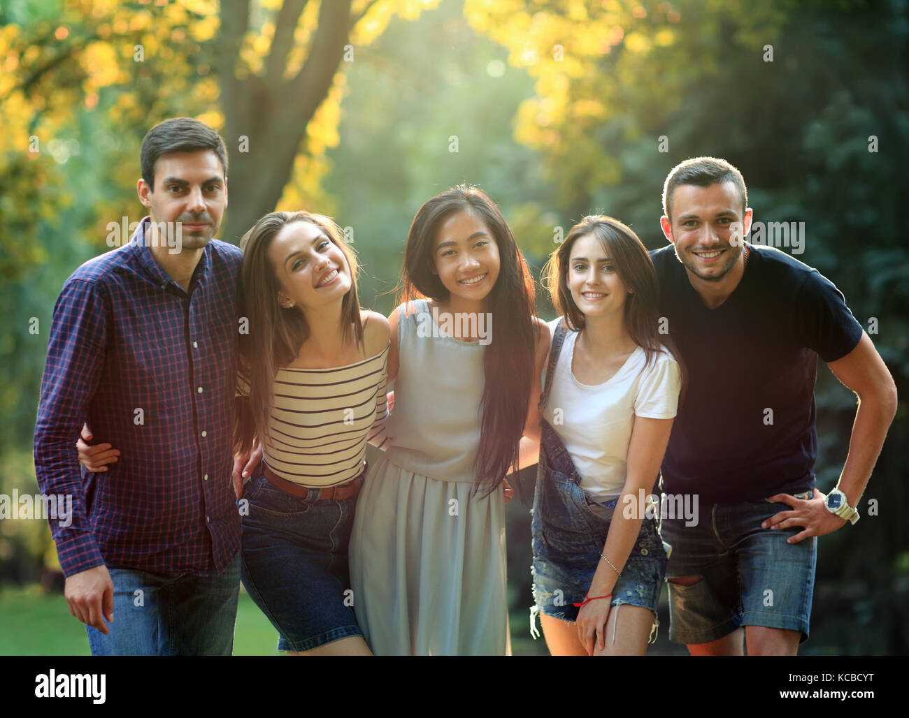 Five young people friends looking at camera in sunny park. Beautiful ...
