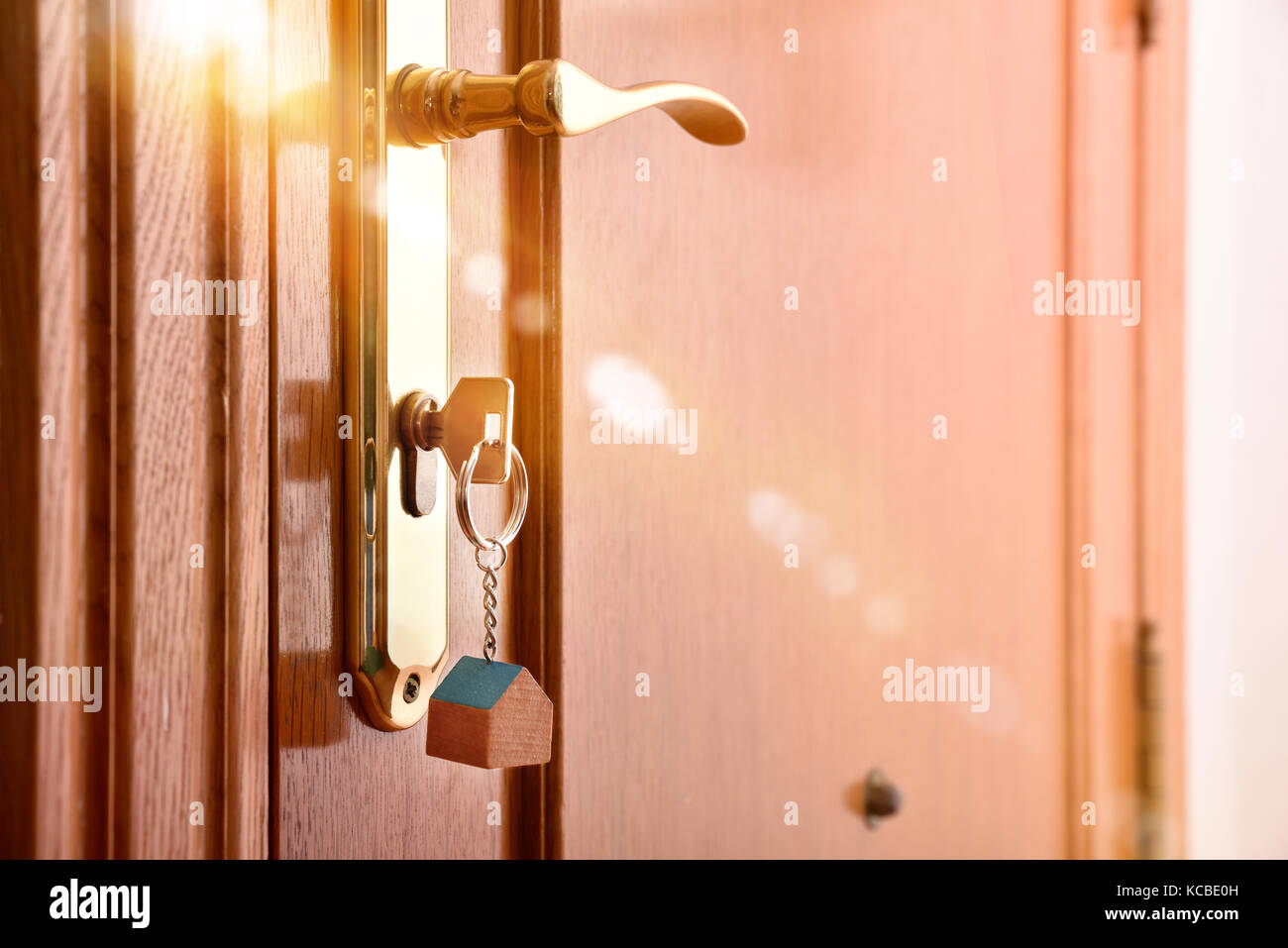 Entrance door detail of a house with keys in the lock with golden light ...