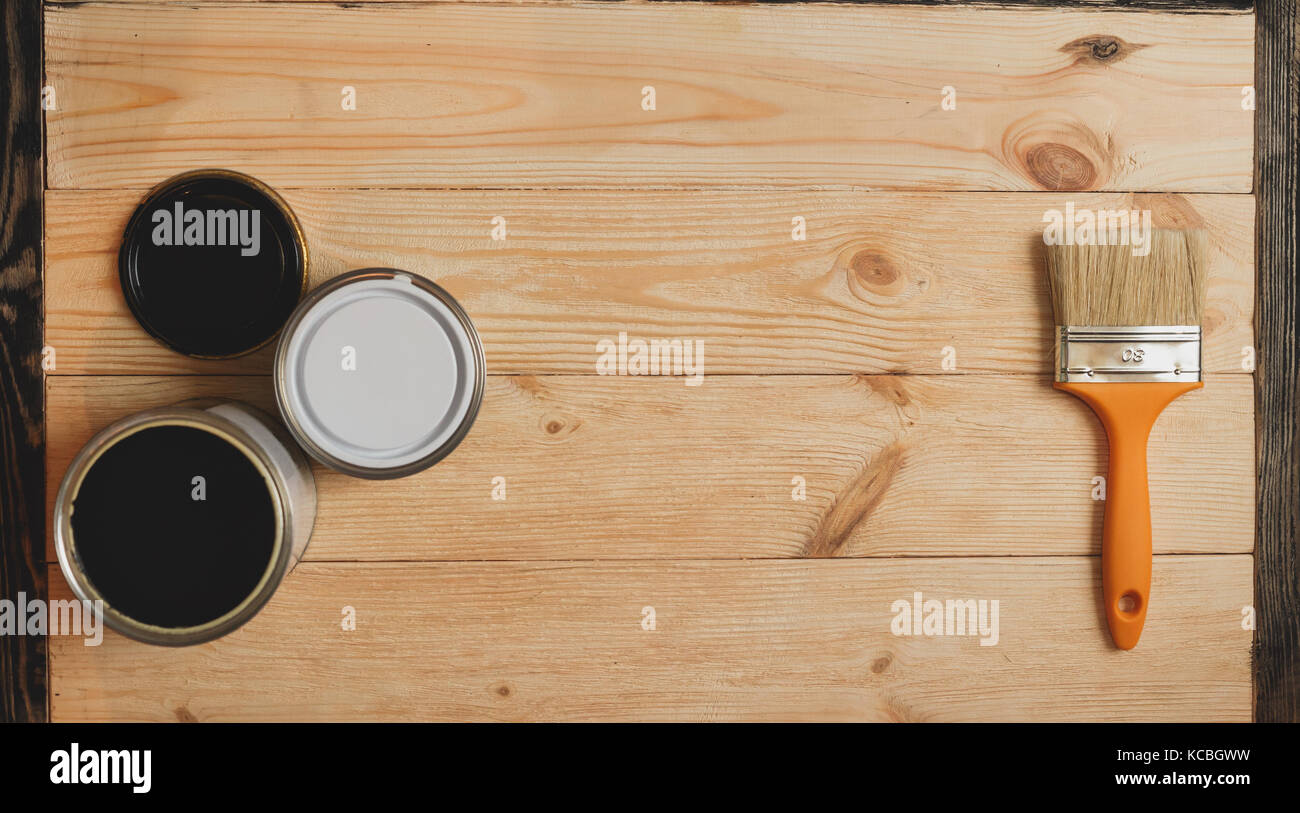 Two paint tins and brush on wooden background with copy space in center ...
