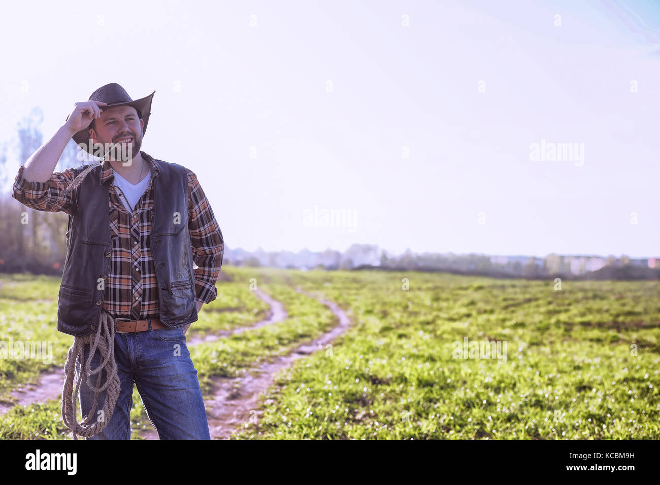 Cowboy standing in a field at sunset Stock Photo - Alamy