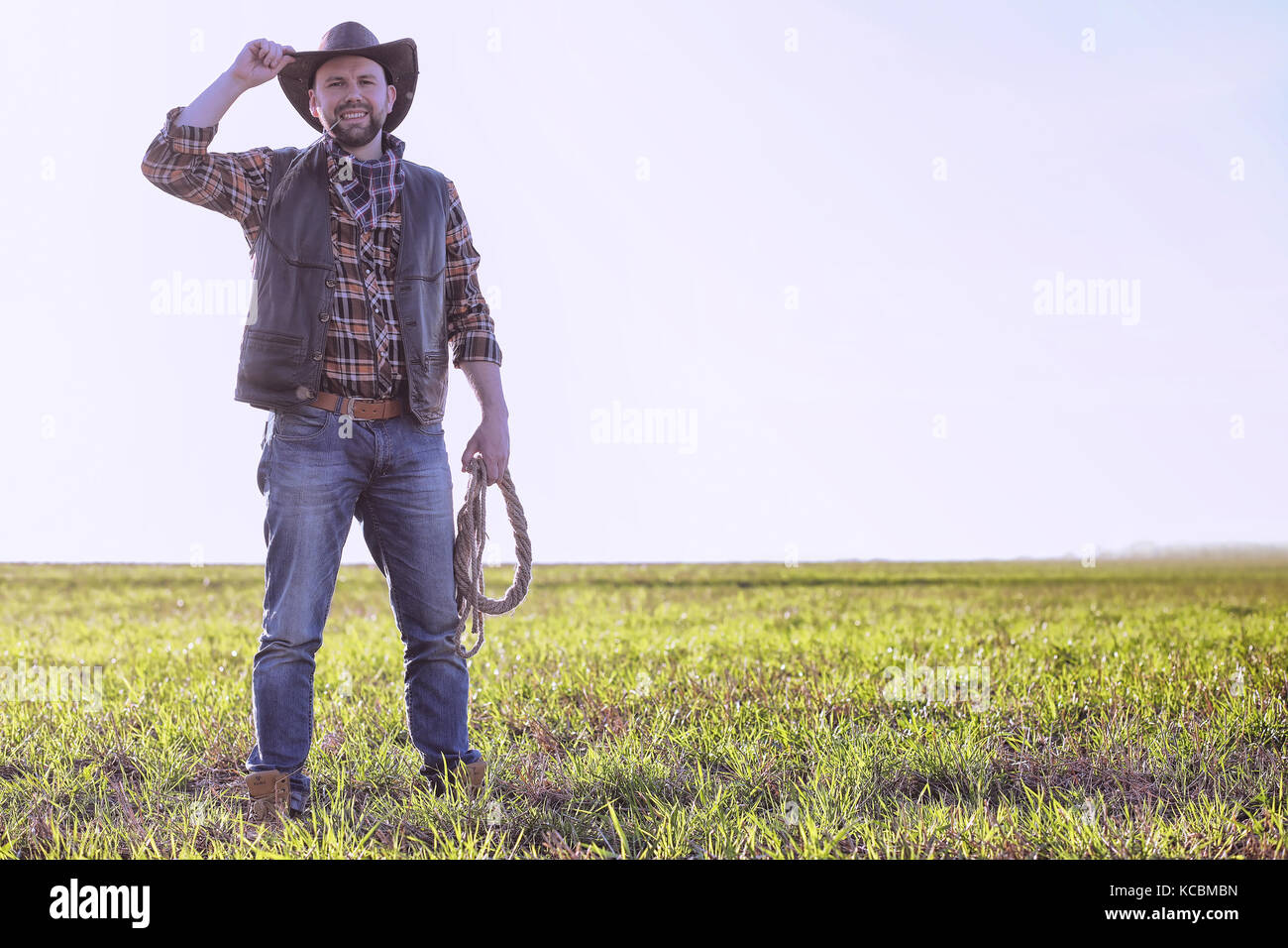 Cowboy standing in a field at sunset Stock Photo - Alamy