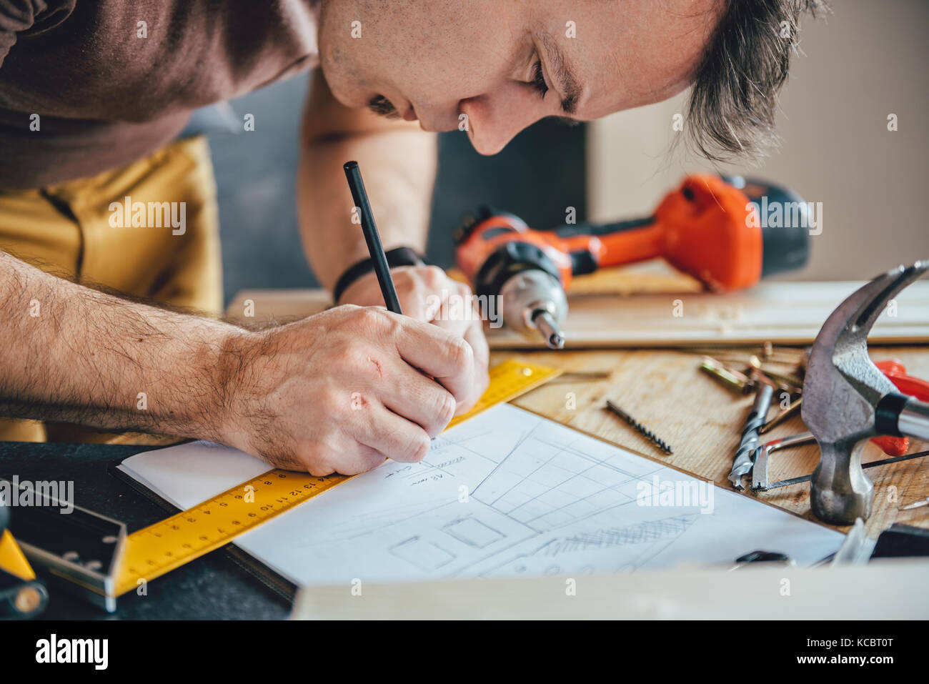 Man making draft plan with pencil on the table with power drills and ...
