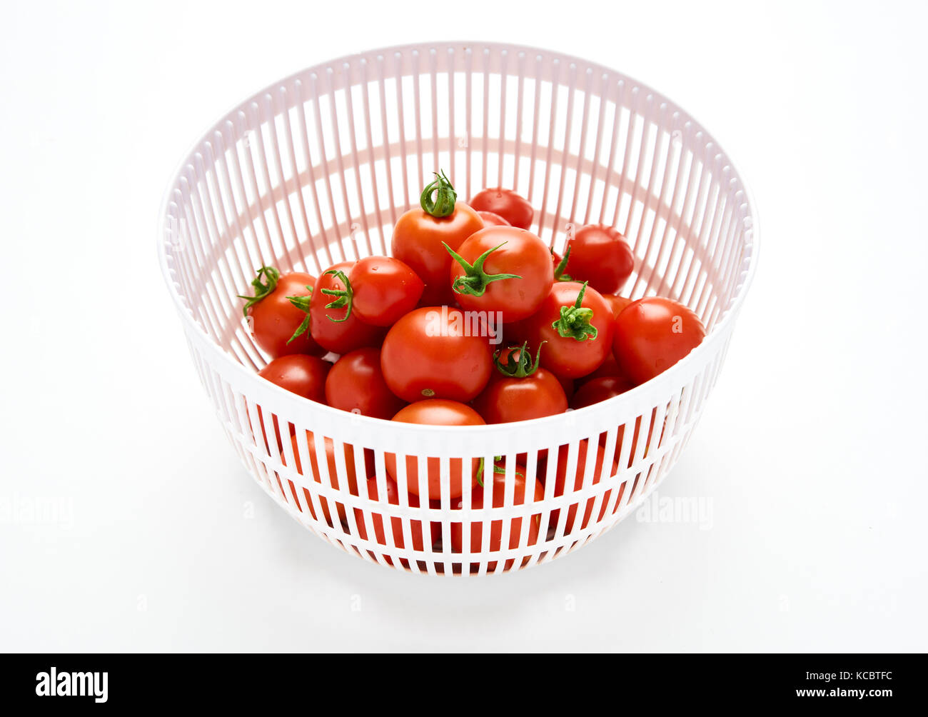 Fresh ripe red tomatoes in a colander isolated on a white background ...