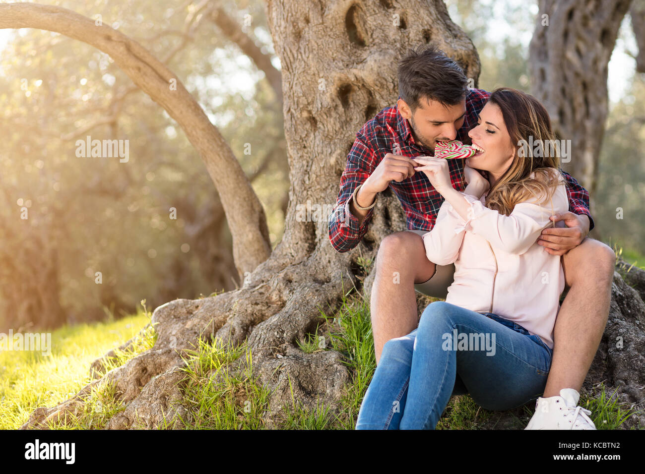 Young beautiful couple under tree in beautiful nature Stock Photo - Alamy