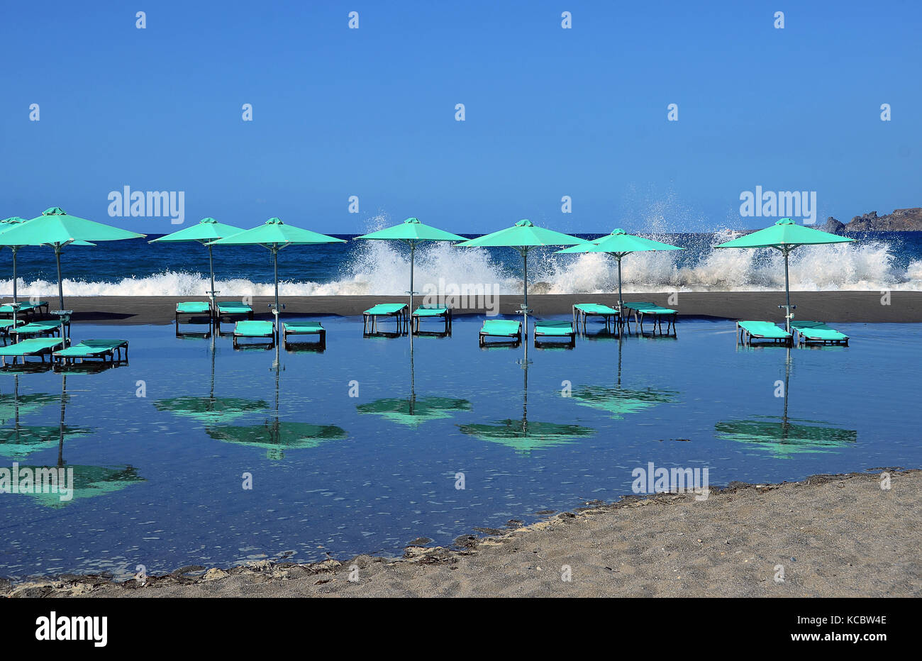 Green umbrellas and sun loungers, surf, water reflection, Plakias ...