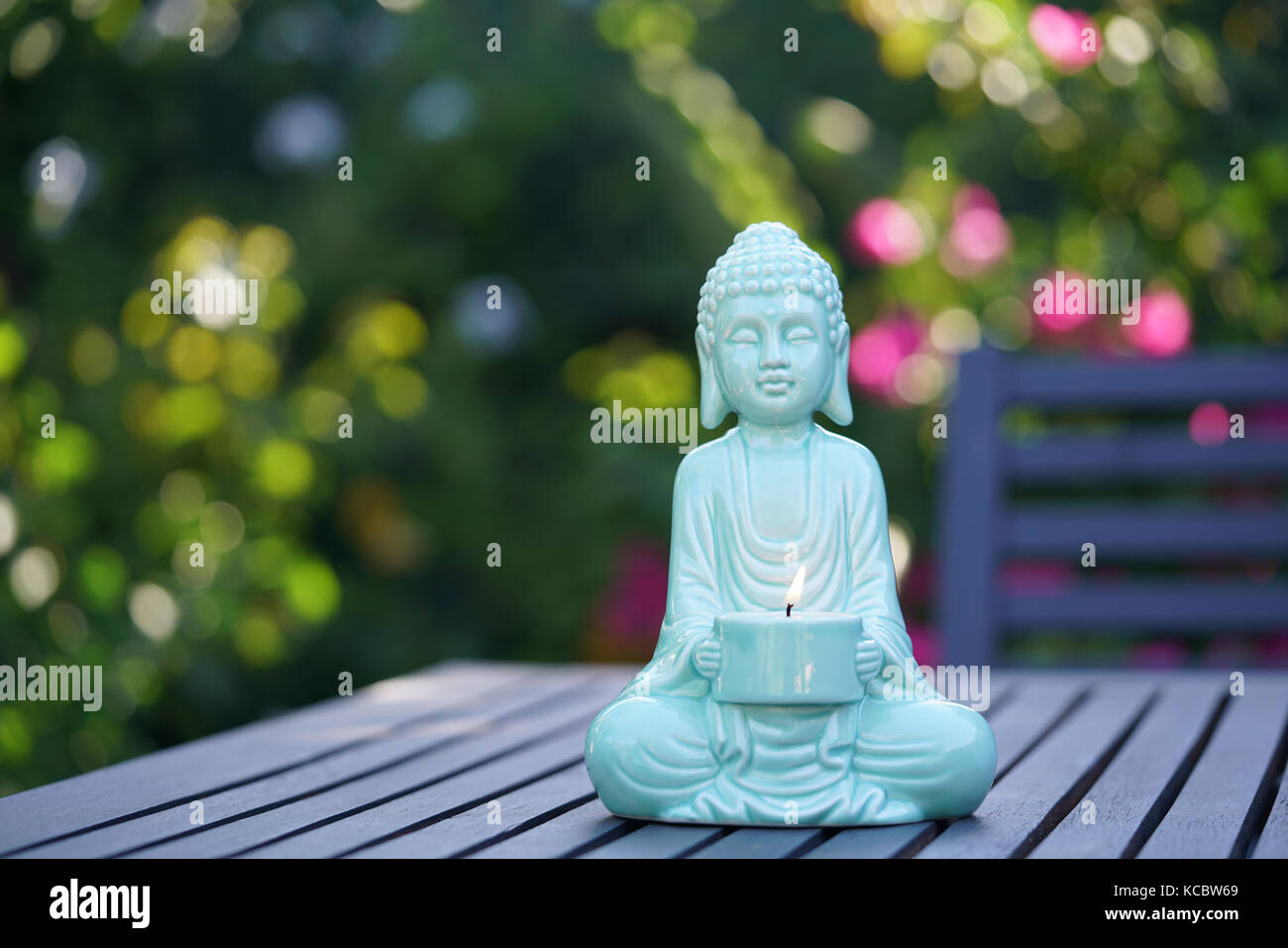 Aqua blue Buddha statue in colorful garden setting Stock Photo - Alamy