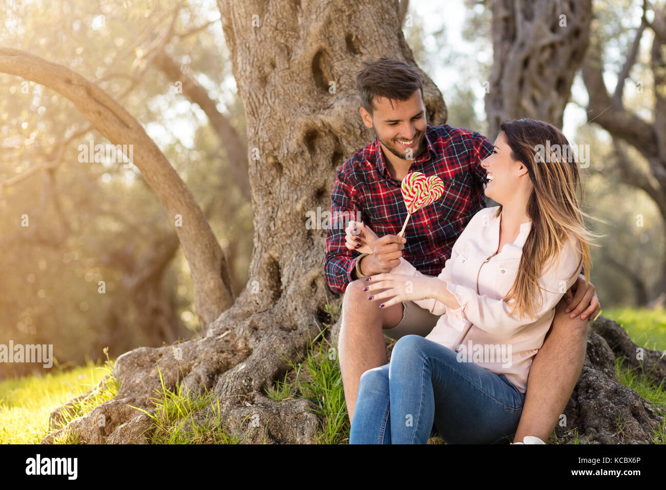 Young beautiful couple under tree in beautiful nature Stock Photo - Alamy