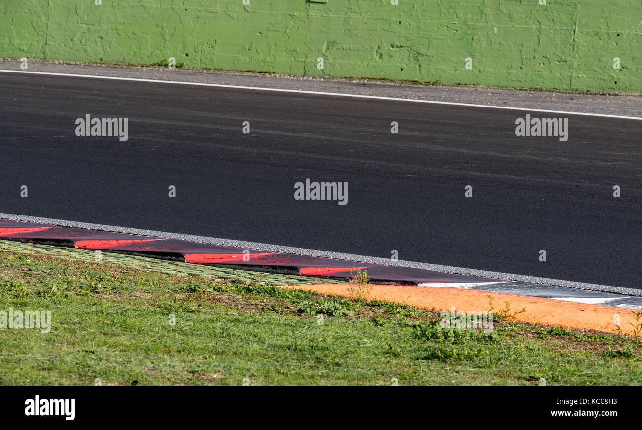 Curb and turn detail on motor racing circuit round, green field on the ...