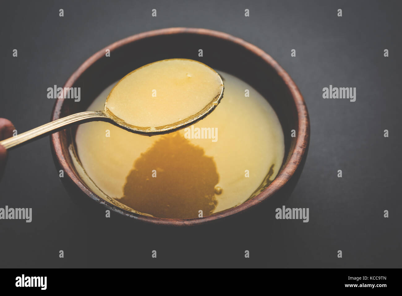 Ghee or clarified butter close up in wooden bowl and silver spoon ...