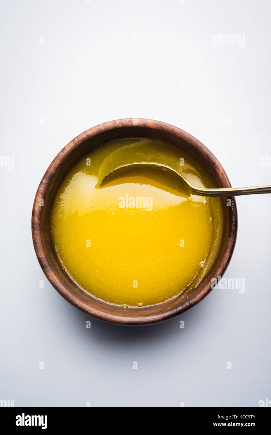 Ghee or clarified butter close up in wooden bowl and silver spoon ...