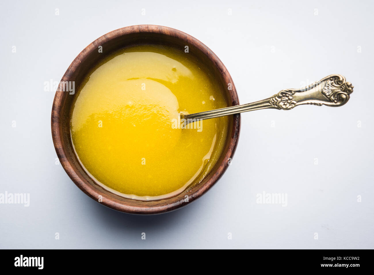 Ghee or clarified butter close up in wooden bowl and silver spoon ...