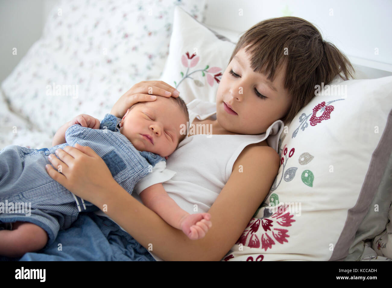 Beautiful boy, hugging with tenderness and care his newborn baby ...