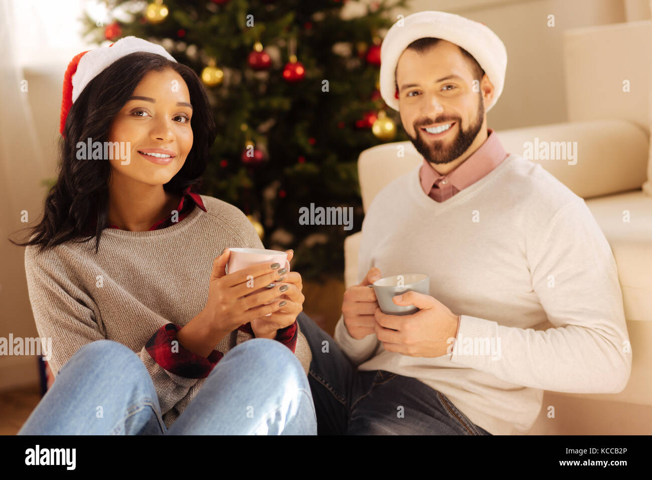 Lovely couple in Santa hats posing with coffee cups Stock Photo - Alamy