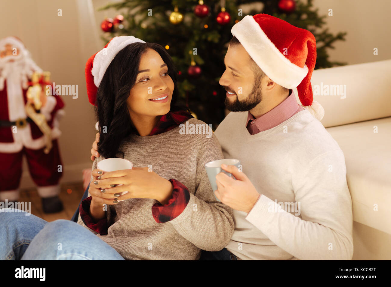 Happy couple in Santa hats looking at each other admiringly Stock Photo ...