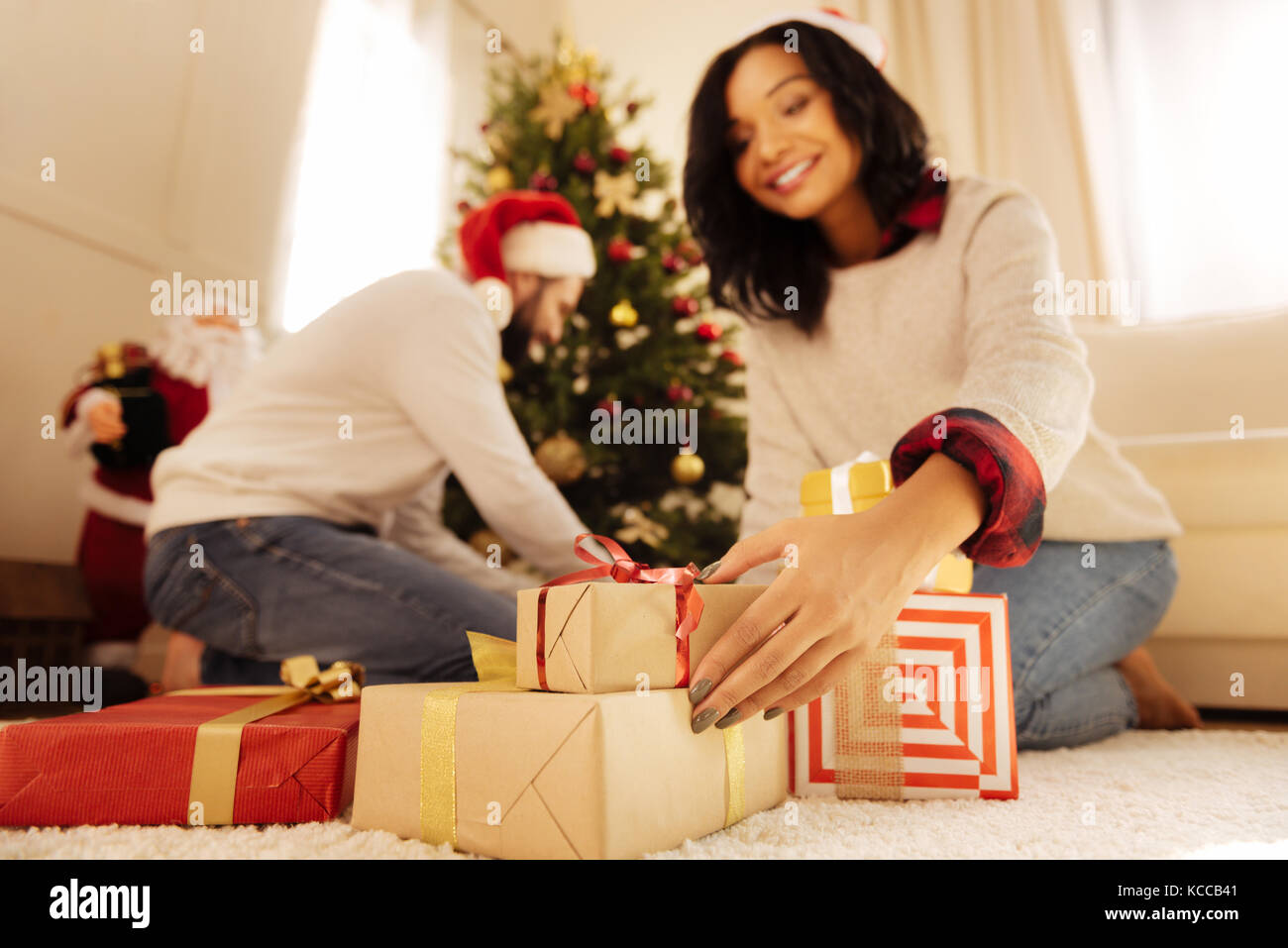 Joyful couple putting presents under Christmas tree Stock Photo - Alamy
