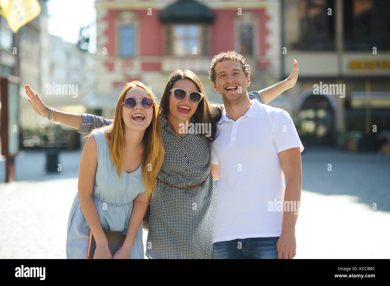 Three young people stand on the square of the ancient city. They are ...