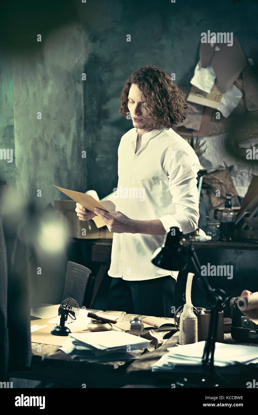 Writer at work. Handsome young writer standing near the table and ...