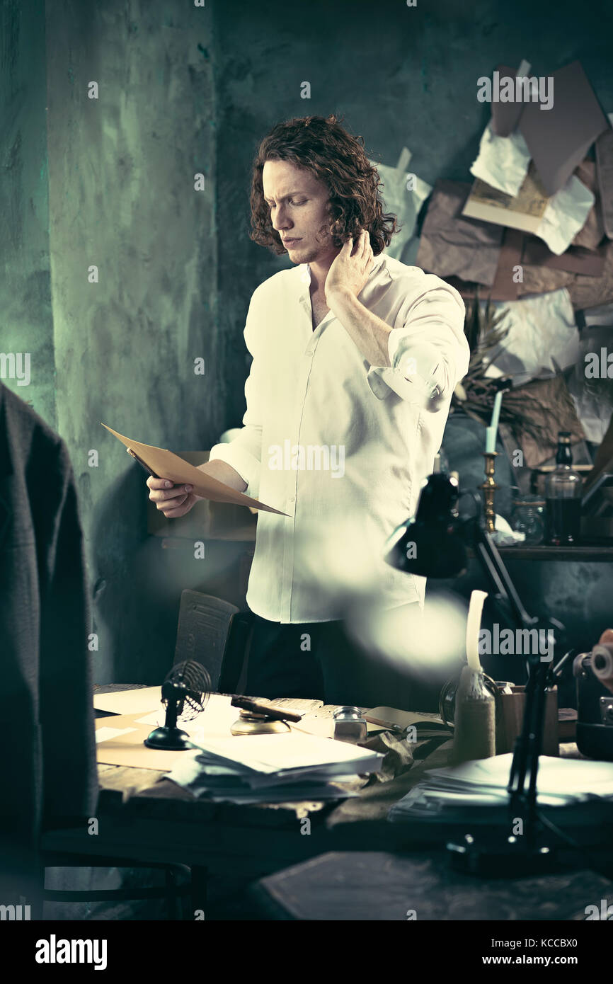 Writer at work. Handsome young writer standing near the table and ...