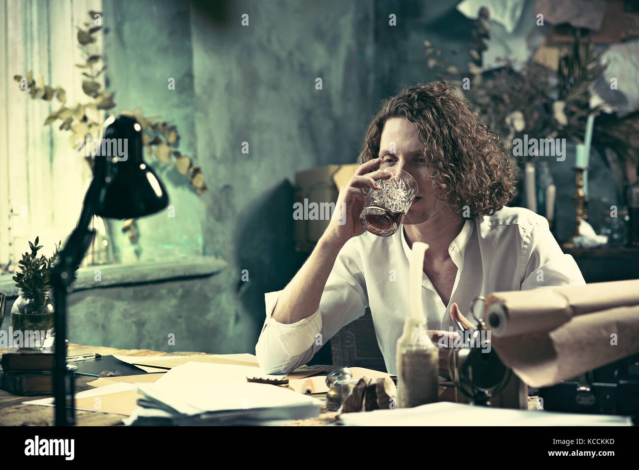 Writer at work. Handsome young writer sitting at the table and writing ...