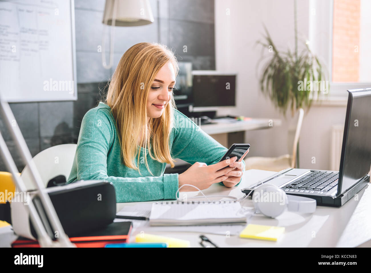 Business woman using smart phone and sitting at the desk in the office ...