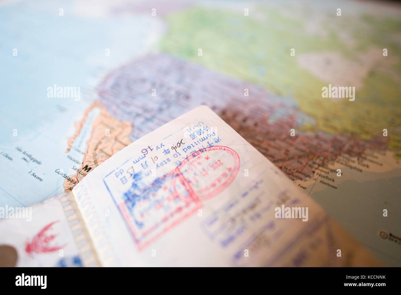 (Selective focus) A passport with stamps is on a blurred geographical ...