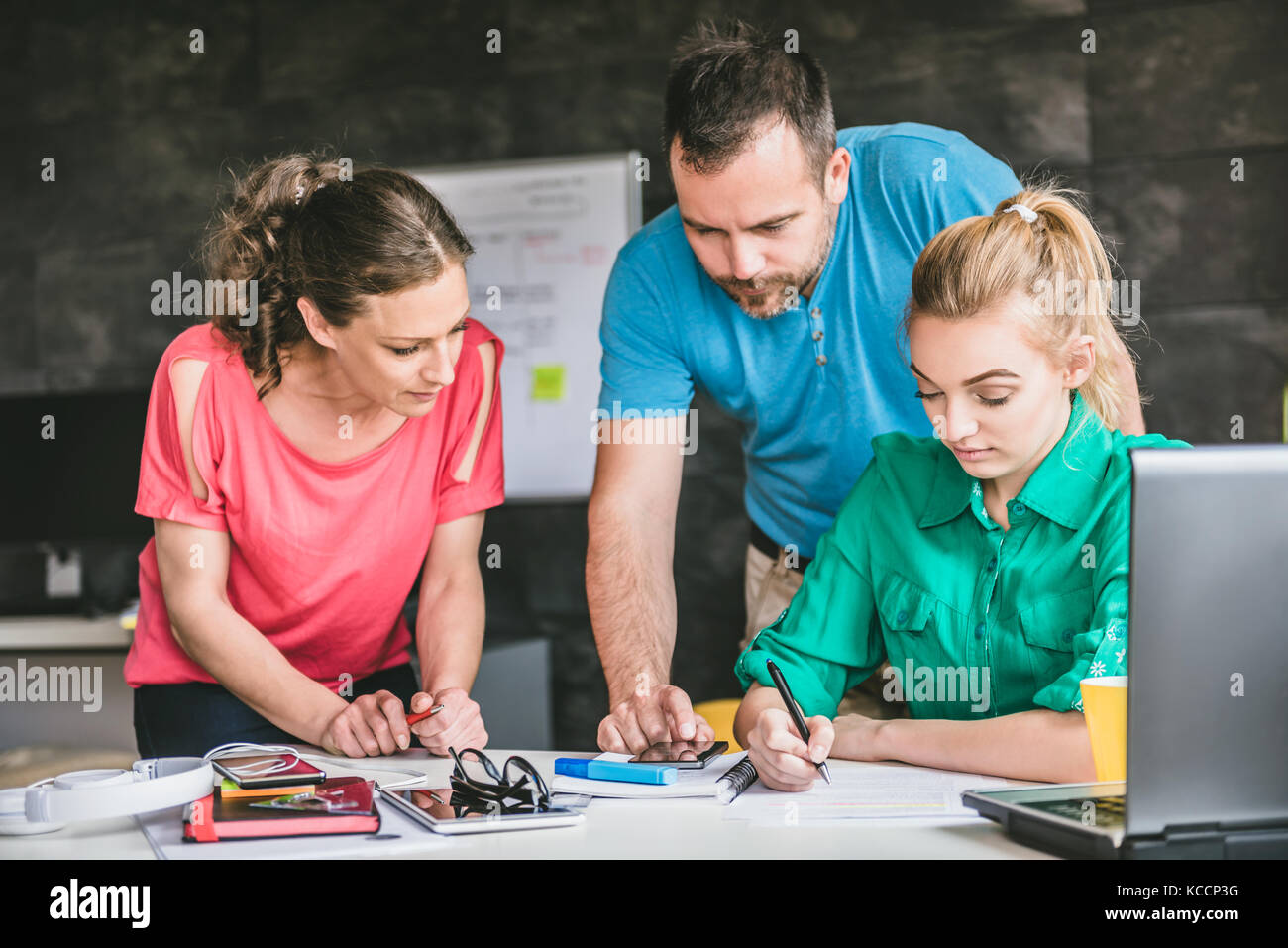 Group of people standing over the desk and having meeting in the office ...