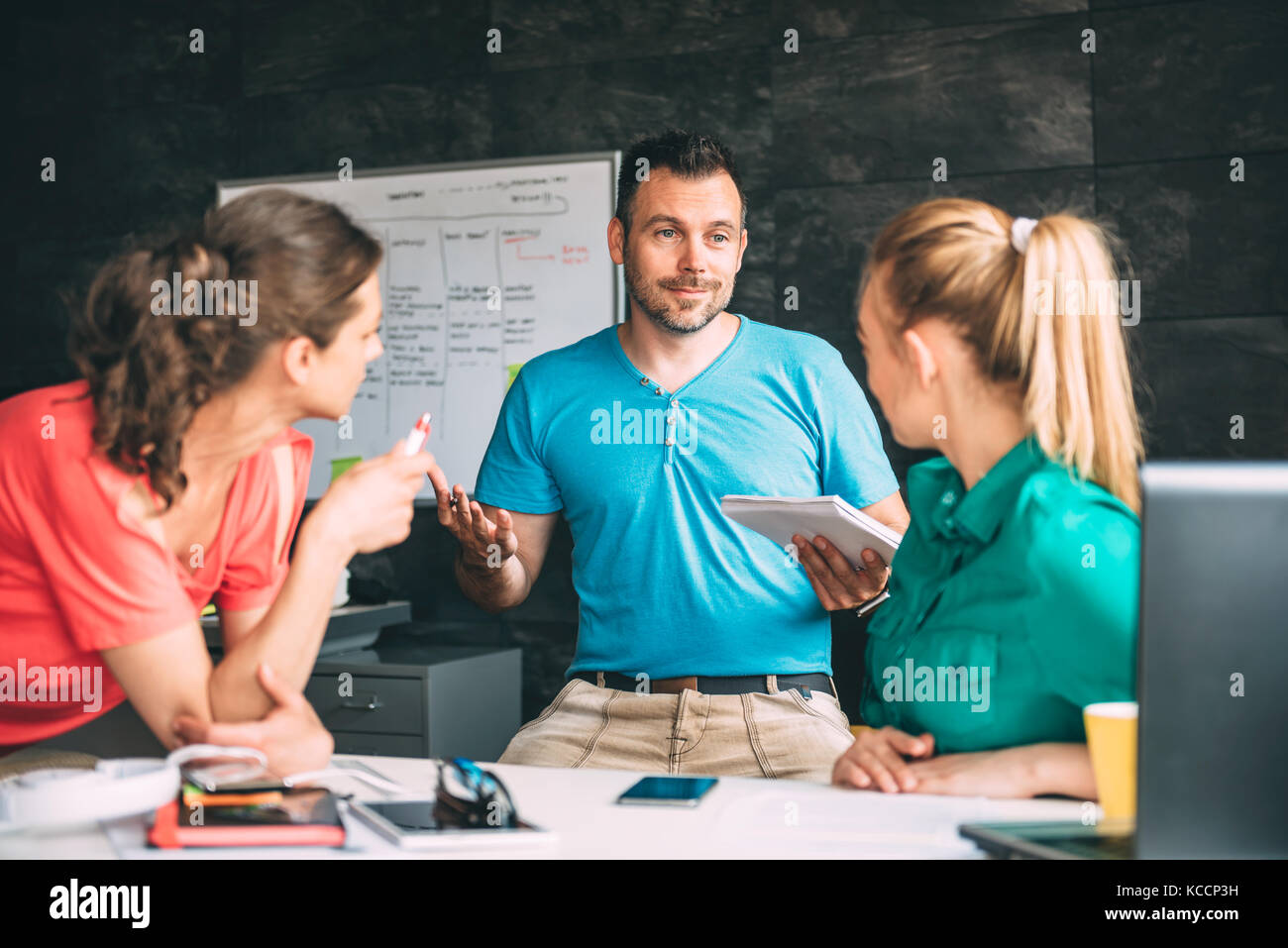 Group of people standing over the desk and having meeting in the office ...