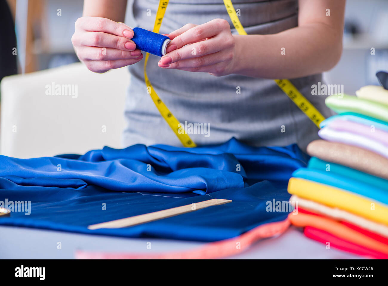 Woman tailor working on a clothing sewing stitching measuring fabric ...