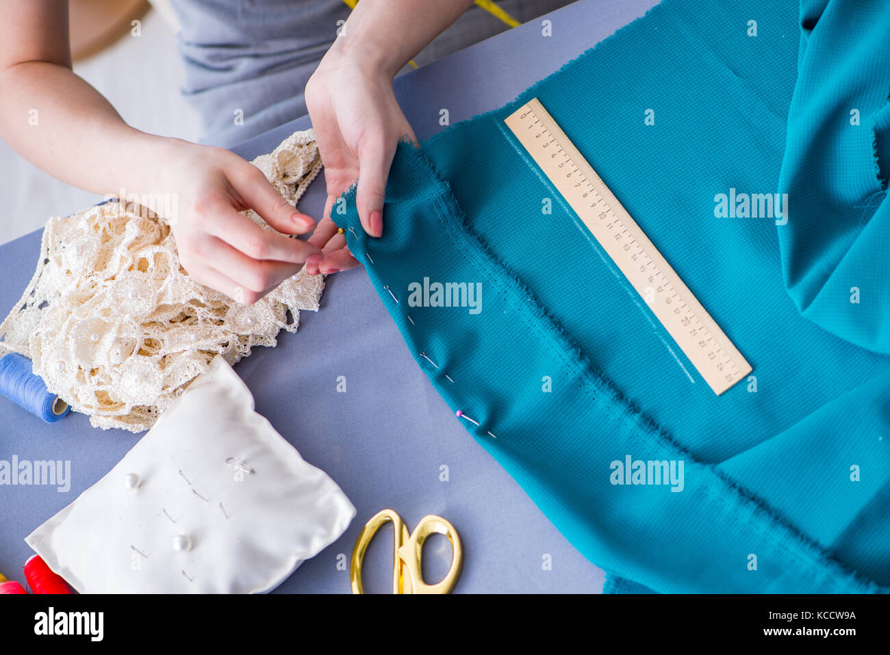 Woman tailor working on a clothing sewing stitching measuring fabric ...