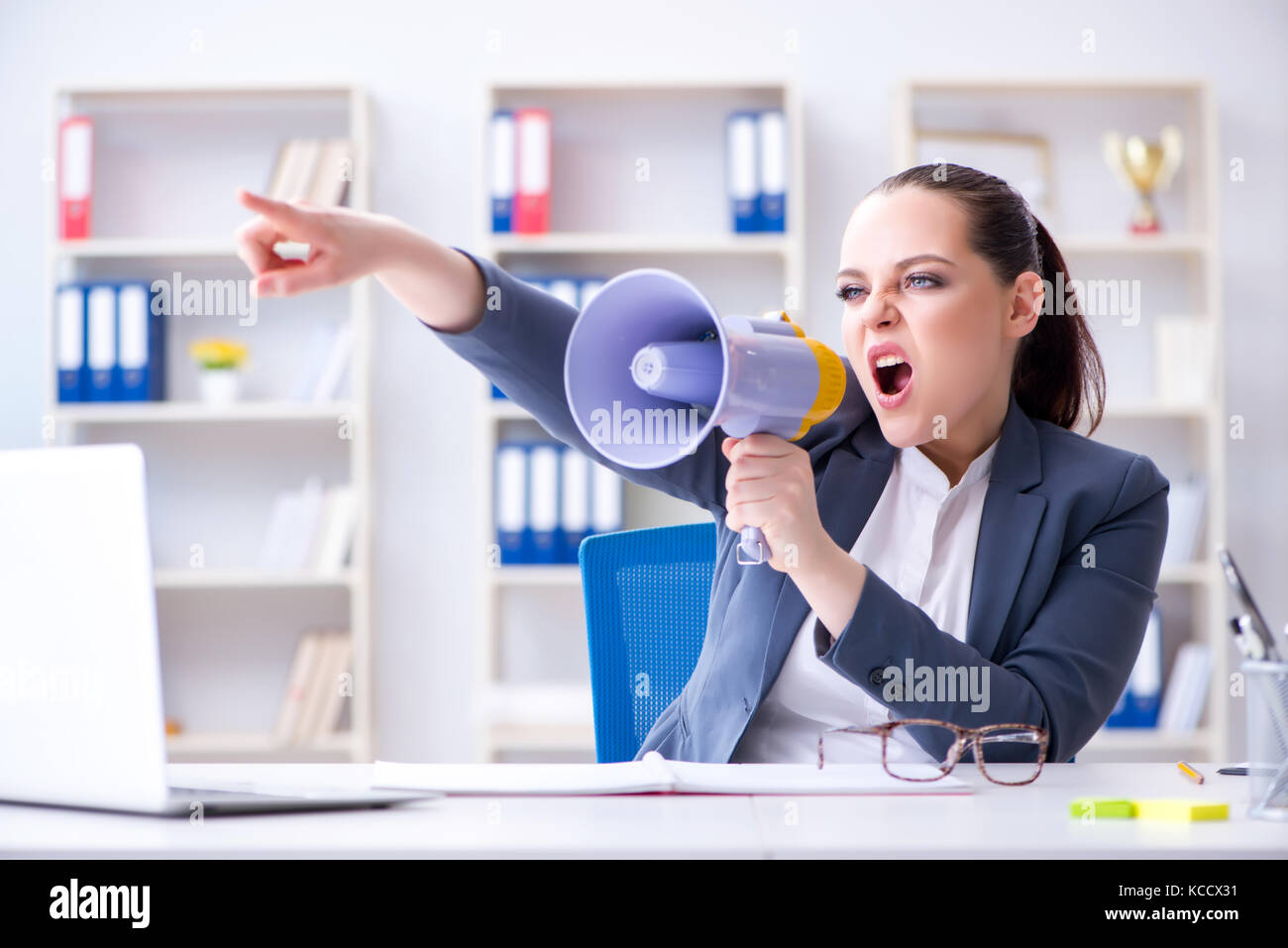 Angry businesswoman yelling with loudspeaker in office Stock Photo - Alamy