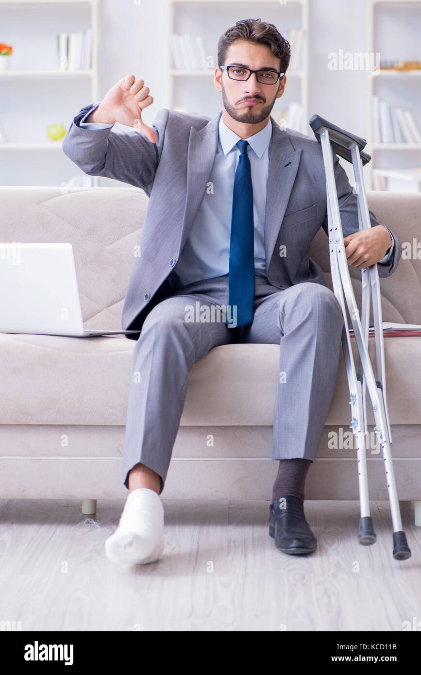 Businessman with crutches and broken leg at home working Stock Photo ...