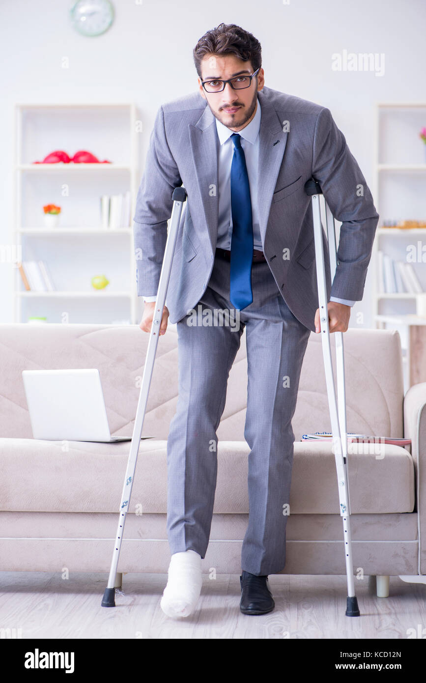 Businessman with crutches and broken leg at home working Stock Photo ...