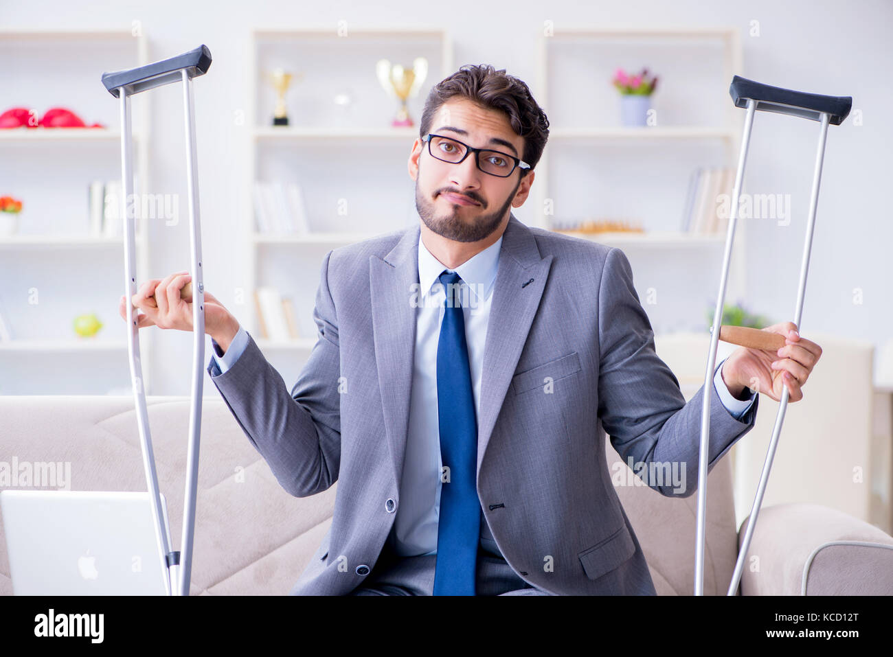 Businessman with crutches and broken leg at home working Stock Photo ...