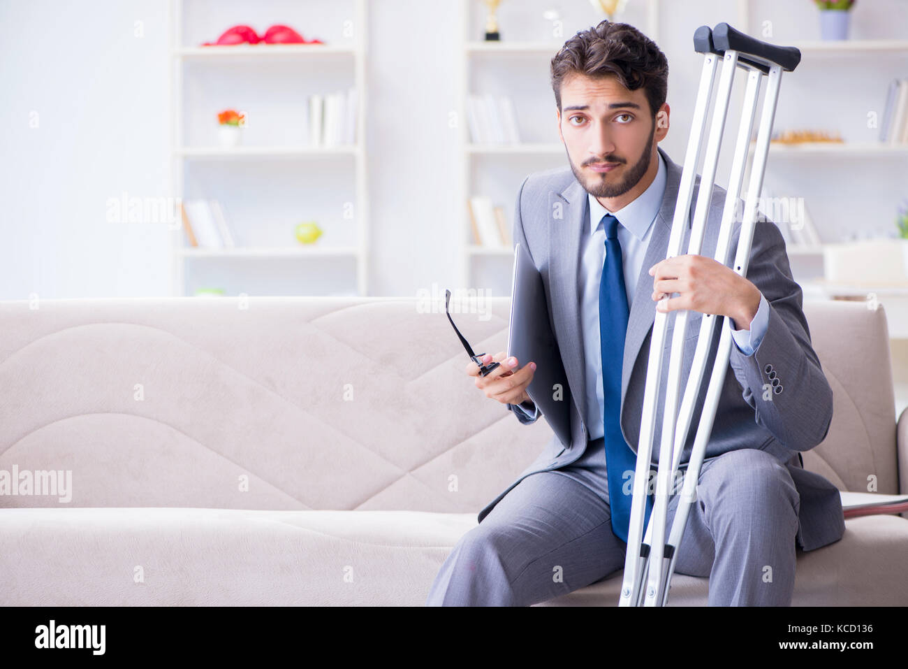 Businessman with crutches and broken leg at home working Stock Photo ...