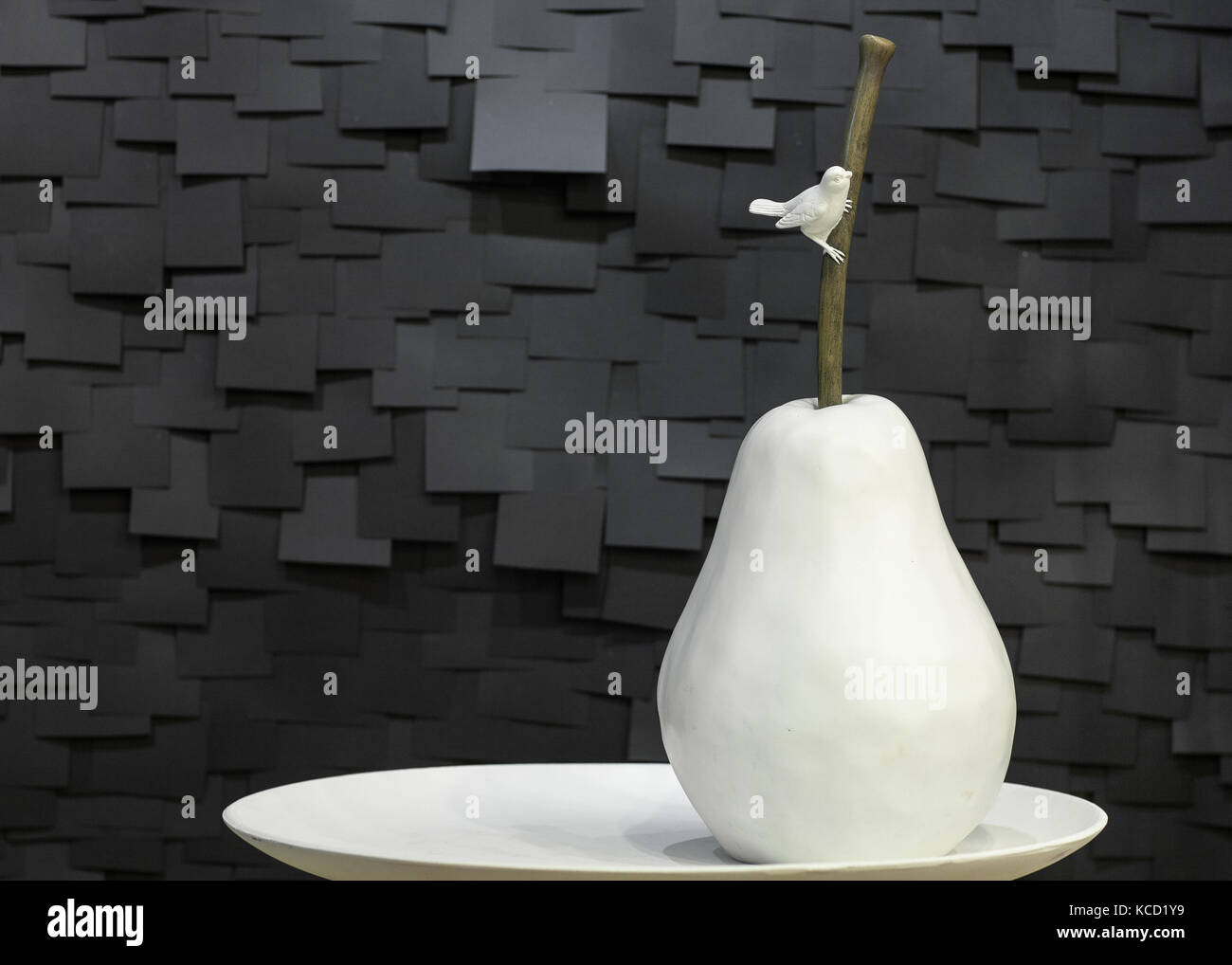 artificial ceramic pear on a plate with a bird on a black background in ...