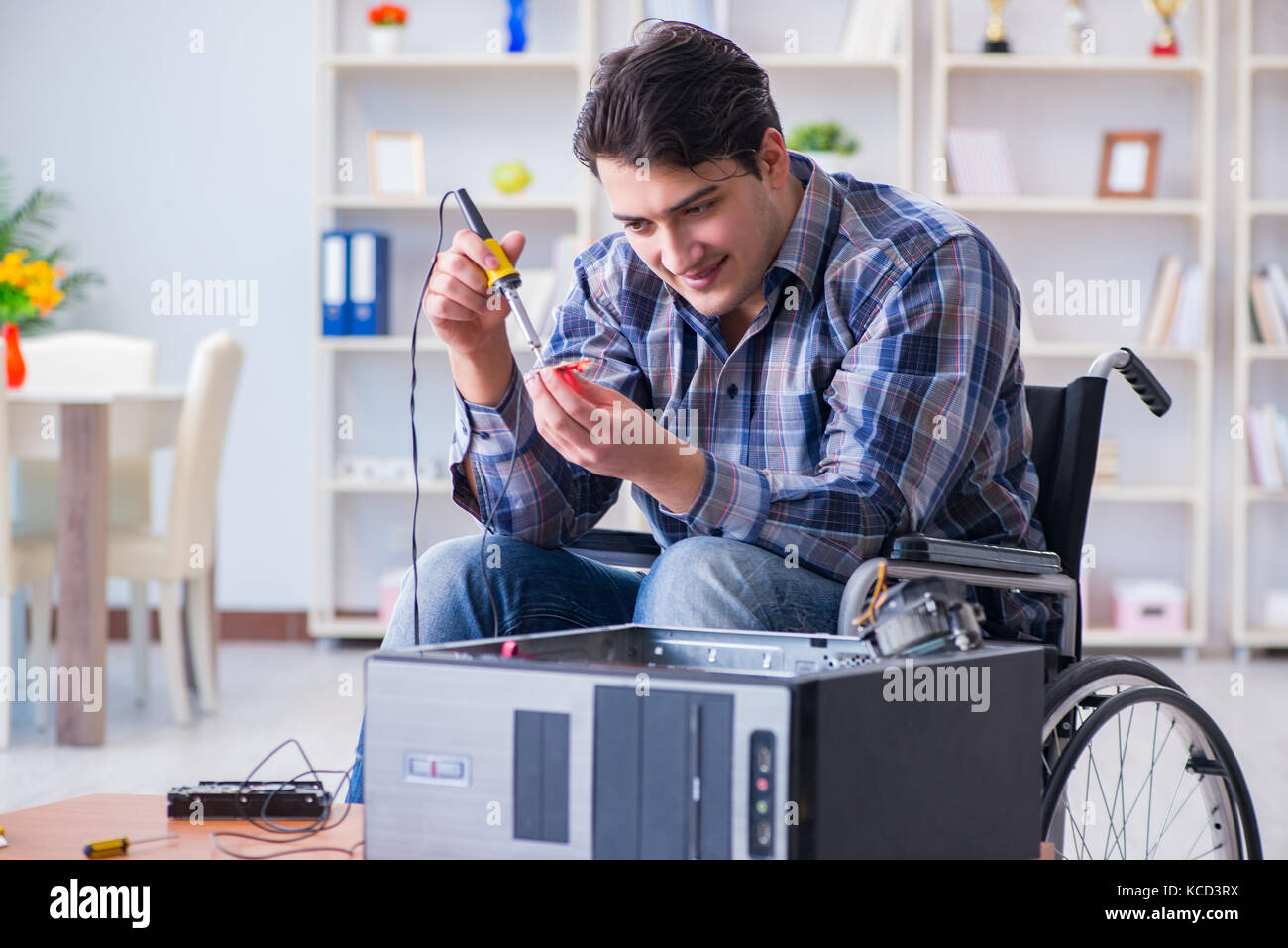 Disabled man on wheelchair repairing computer Stock Photo - Alamy