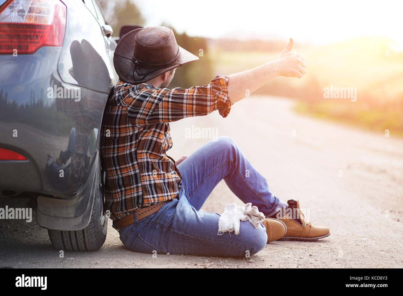 Man is sitting on the road by the car Stock Photo - Alamy