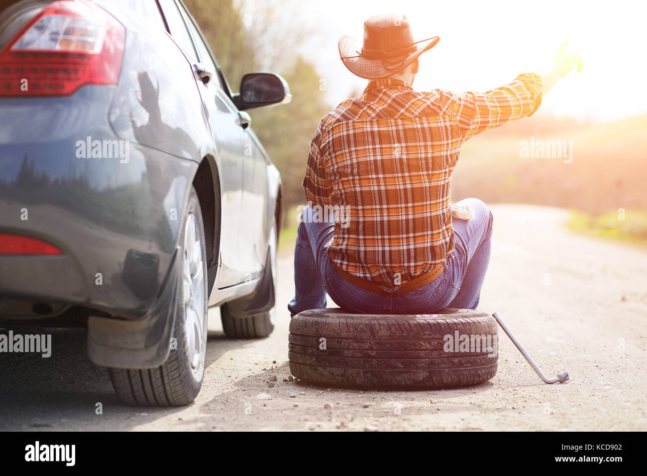 Man is sitting on the road by the car Stock Photo - Alamy