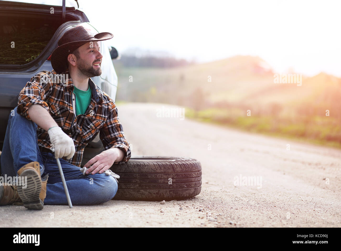 Man is sitting on the road by the car Stock Photo - Alamy