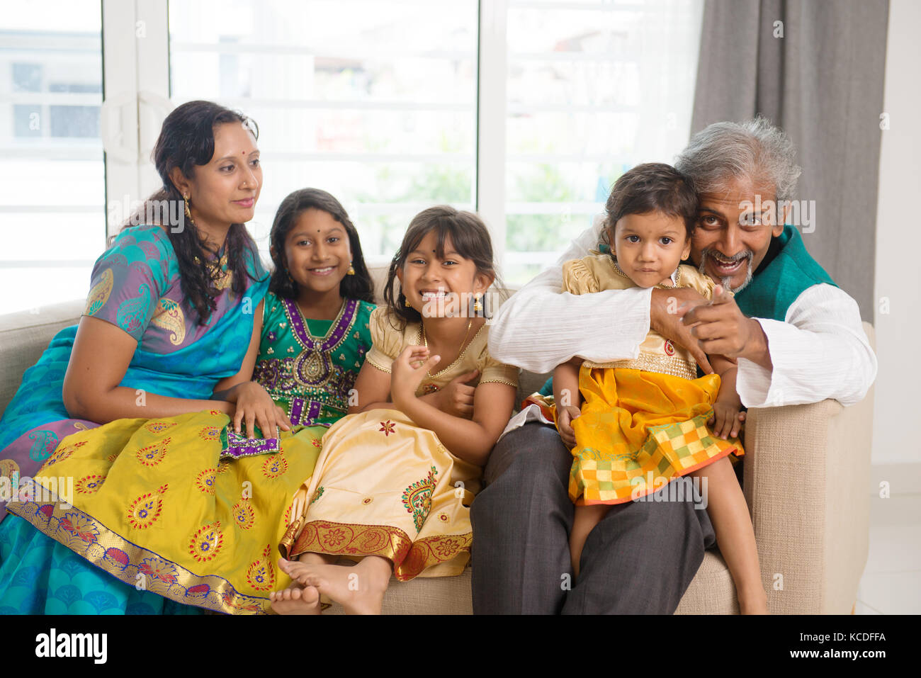Portrait of happy Indian family sitting on couch at home. Asian people ...