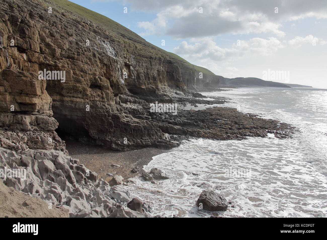 The steep rocks of Ogmore showing a small cave entrance in the high ...
