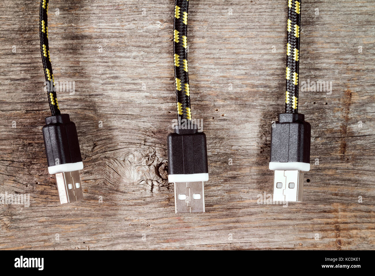 Three USB cables hanging over wooden background Stock Photo - Alamy
