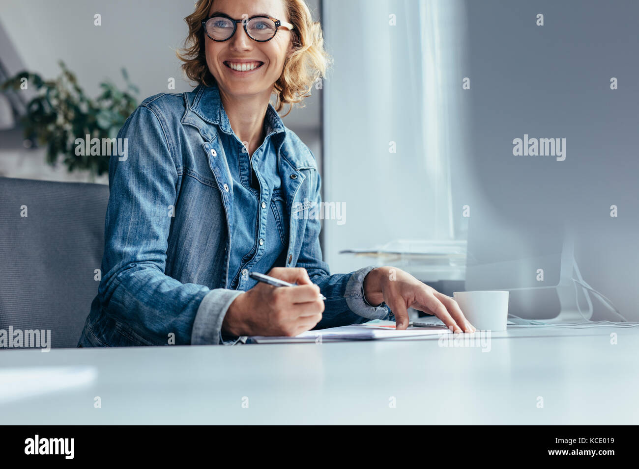 Beautiful young businesswoman sitting in office looking away and ...