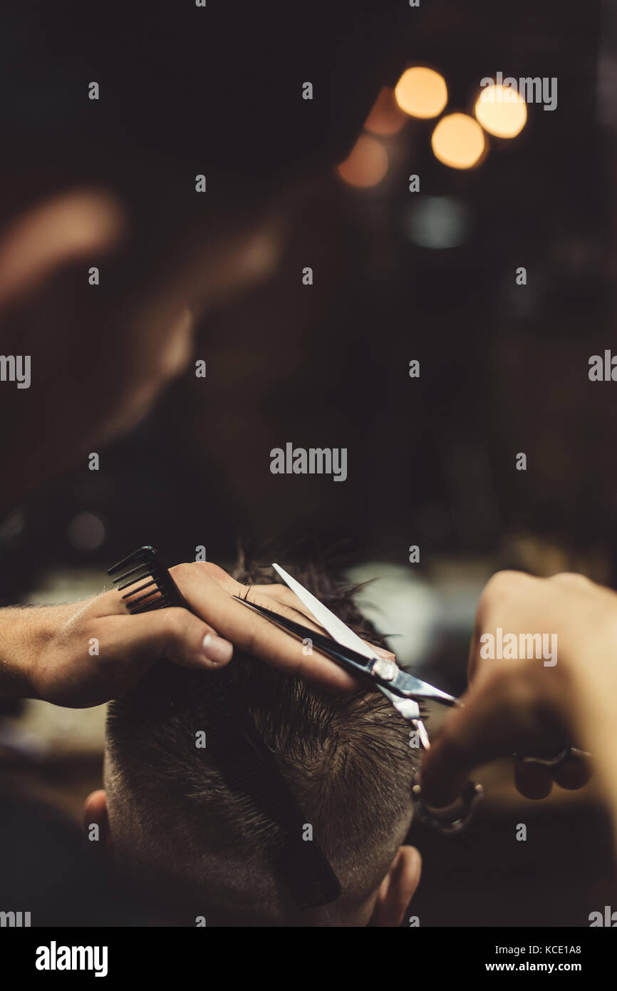 Crop barber doing haircut for client Stock Photo - Alamy
