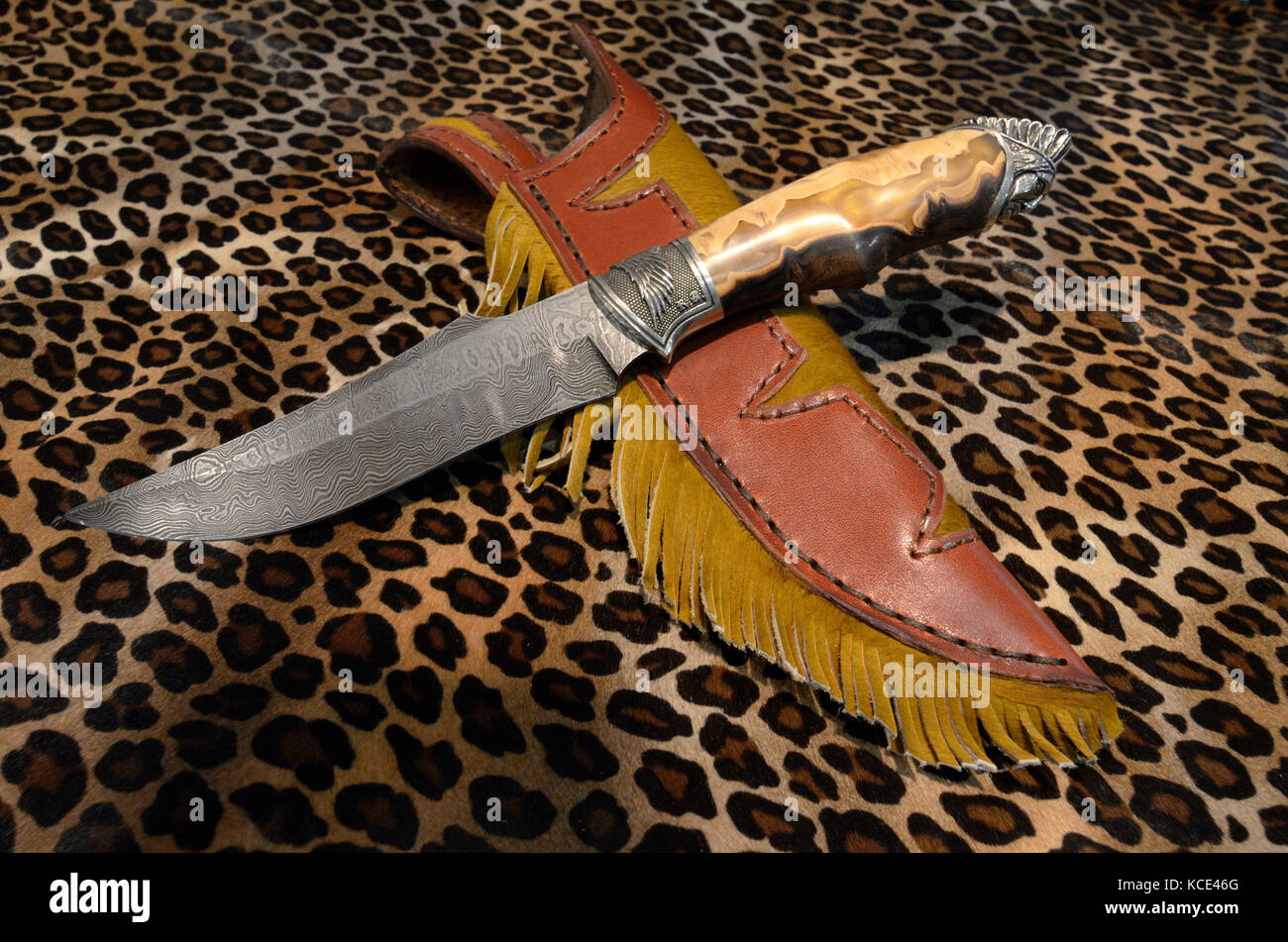 A fixed blade damascus knife and leather sheath displayed on a leopard ...