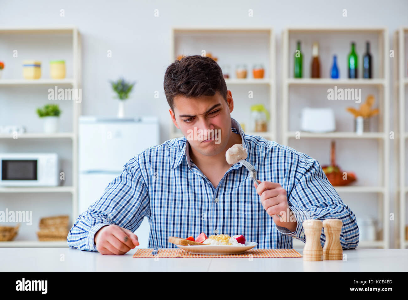 Man eating tasteless food at home for lunch Stock Photo - Alamy