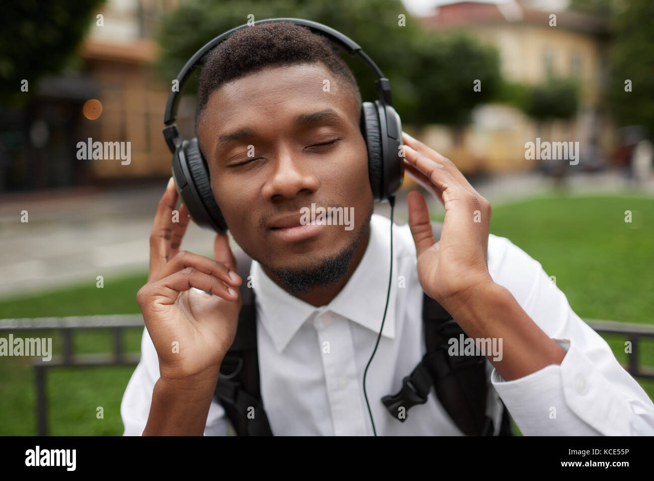 African man listening music in headphones with closed eyes and dreaming ...
