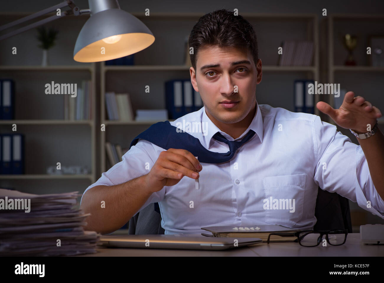 Businessman staying late in office for drugs Stock Photo - Alamy