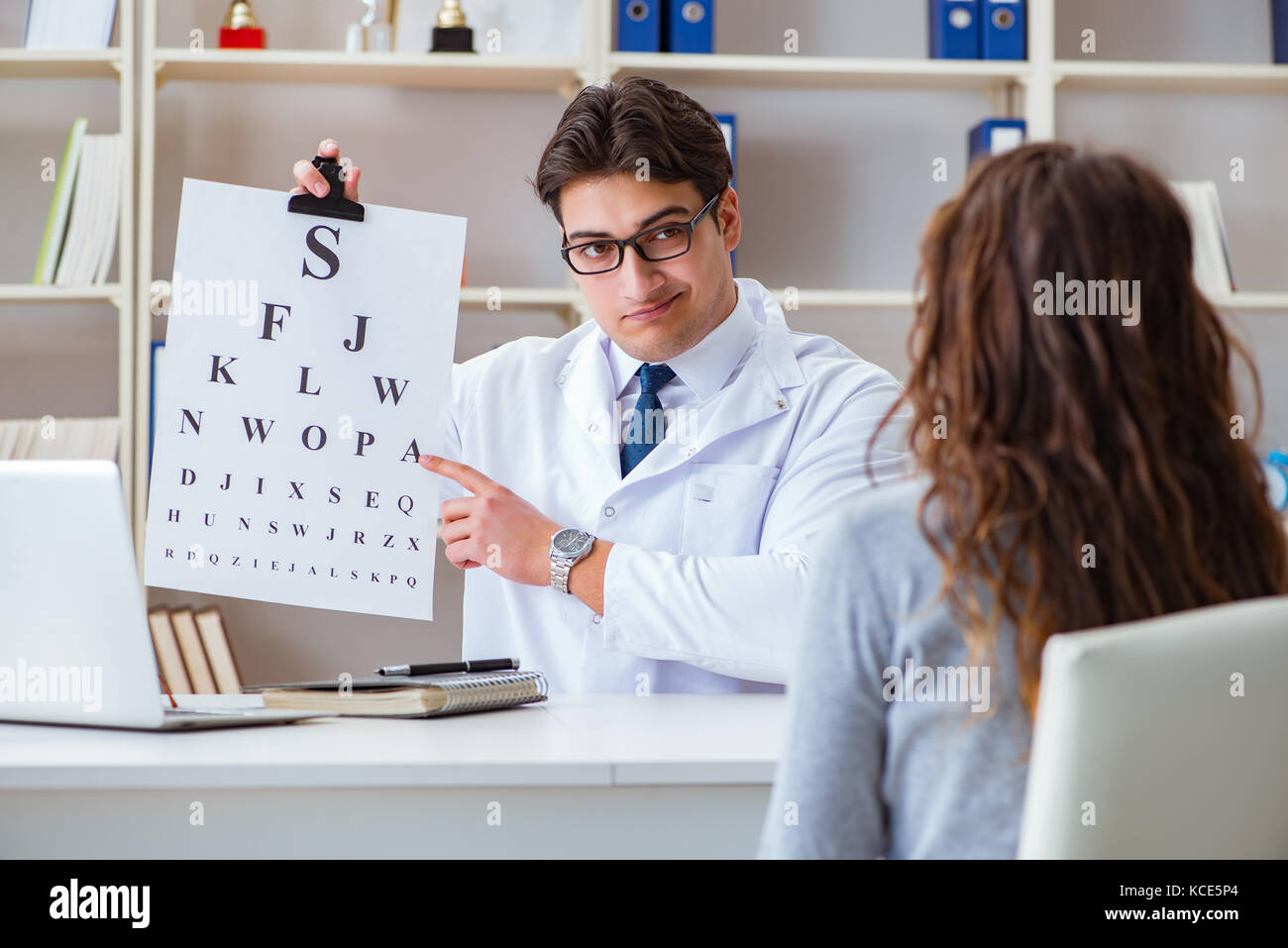 Doctor optician with letter chart conducting an eye test check Stock ...