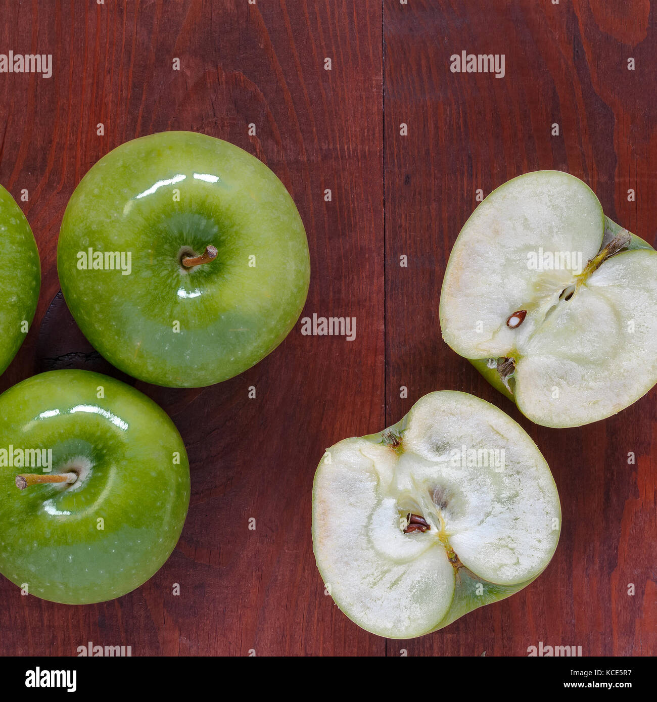 Green ripe apples and apple slices cut on a grey wooden background. Top ...